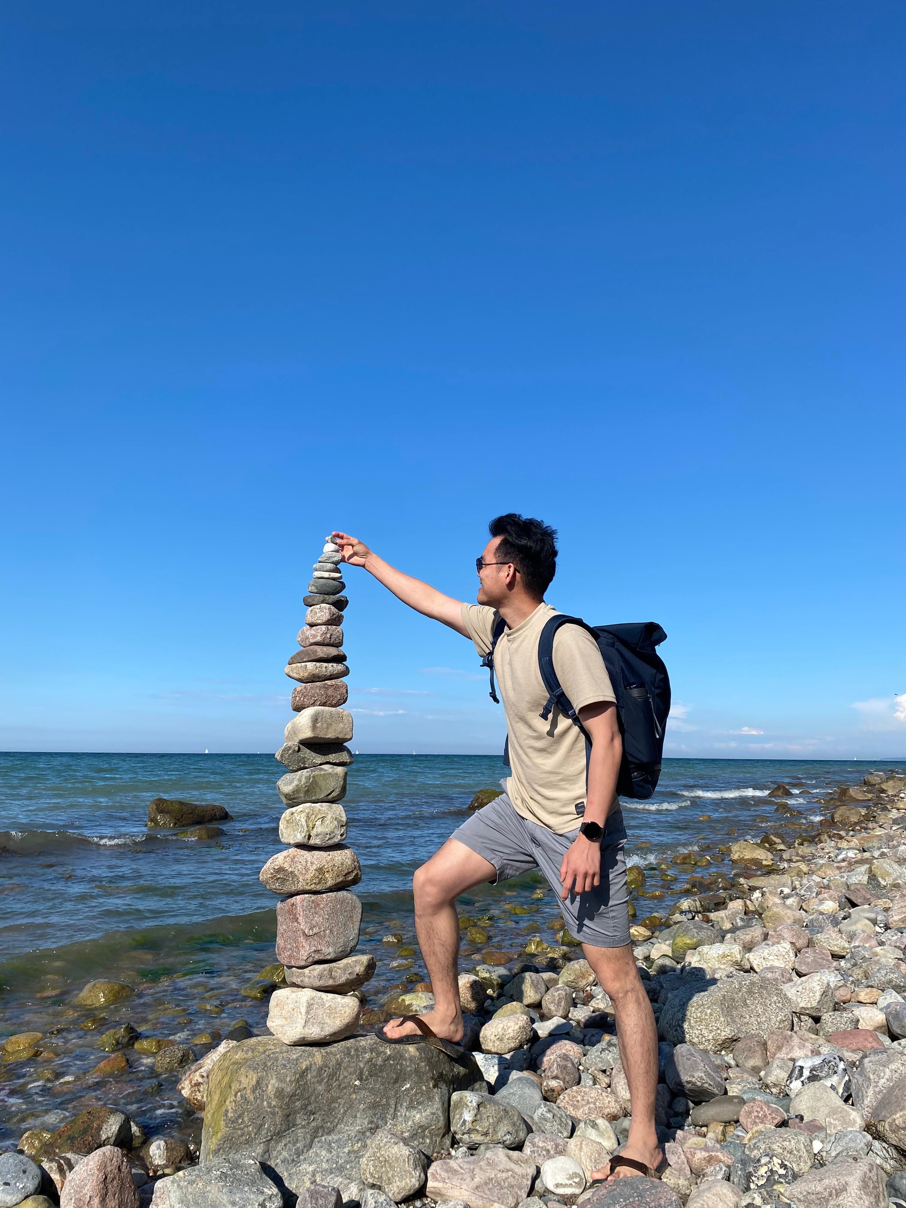 A guy is stacking rocks on the beach